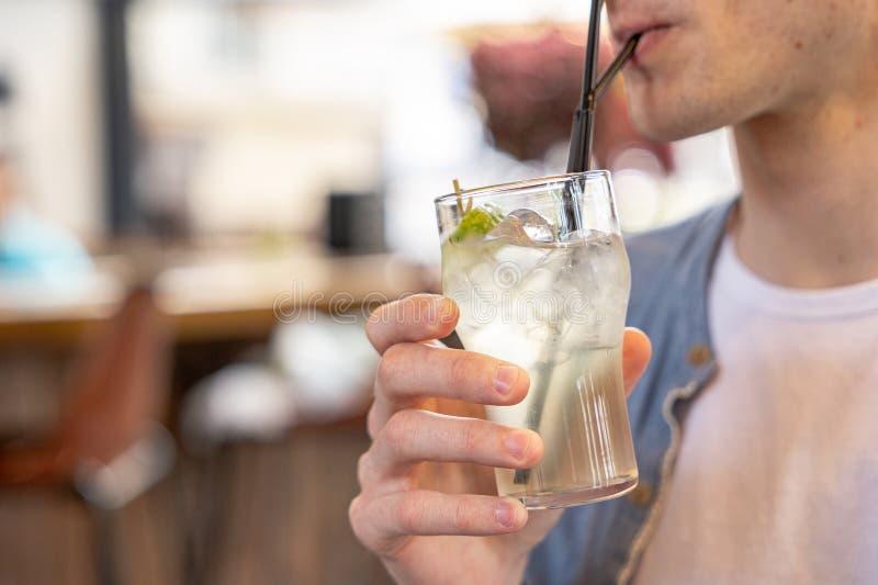 Man Drinks Lemonade through a Straw from Glass with Ice. Stock Image ...