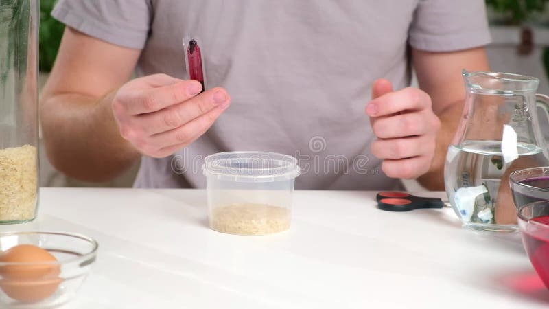 A Man Drips Red Dye into a Container of Rice. an Unusual Way of ...