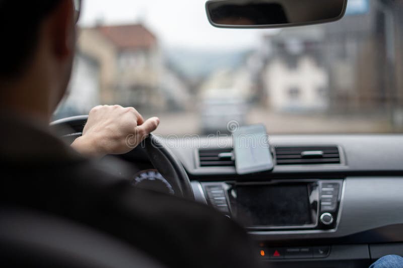 A Man is Currently Driving His Car with a Cell Phone Sitting on the ...