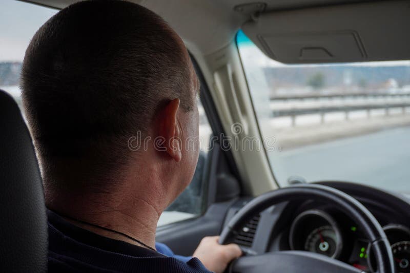 A Man is Driving a Car, Rear View, You Can See the Track in the Window ...