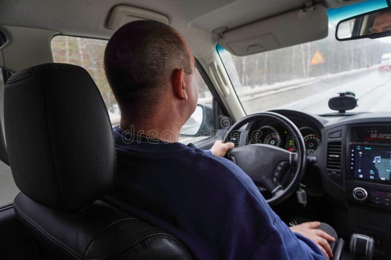 A Man is Driving a Car, Rear View, You Can See the Track in the Window ...
