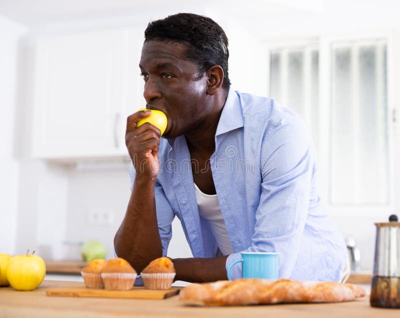 Man Eating Apple in Kitchen at Home Stock Photo - Image of kenyan ...