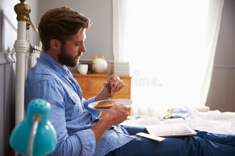 Man Eating Breakfast in Bed Whilst Using Mobile Phone Stock Photo ...