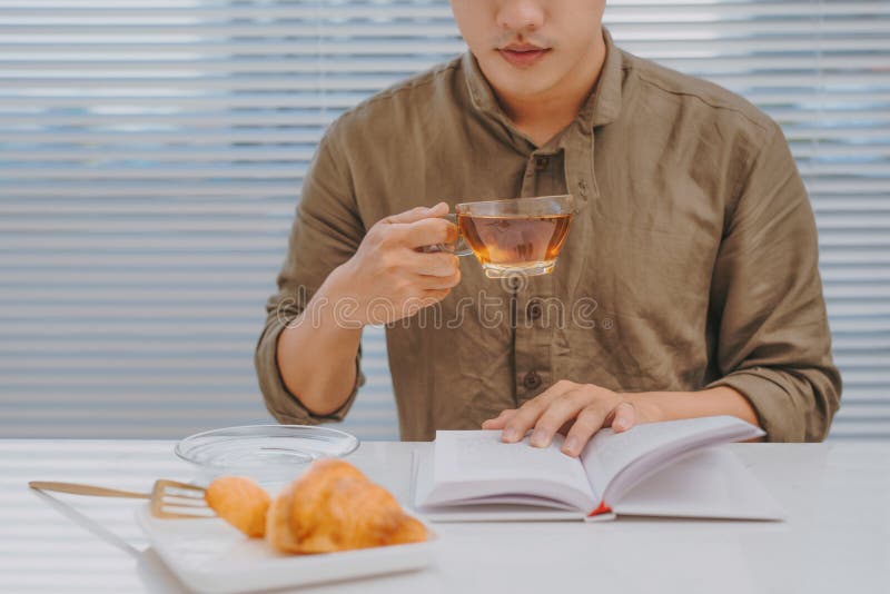 Man Eating Breakfast and Reading Book while Sitting at a White T Stock ...