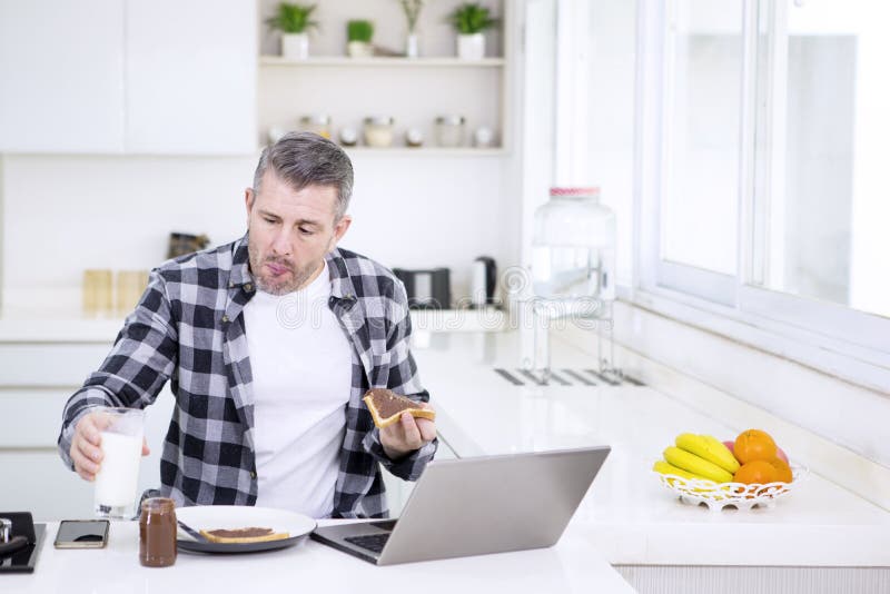 Man Eating Breakfast while Working in the Kitchen Stock Image - Image ...