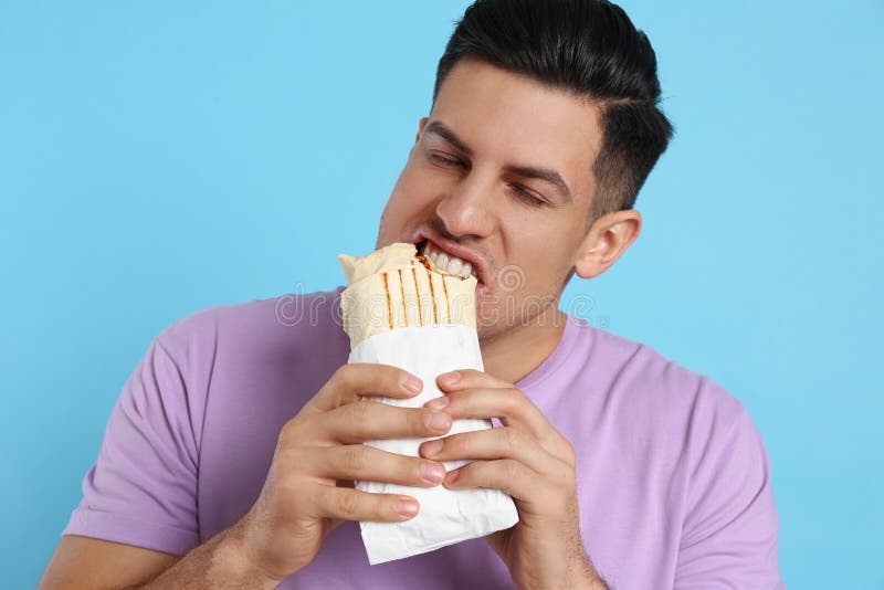 Man Eating Delicious Shawarma on Turquoise Background Stock Image ...