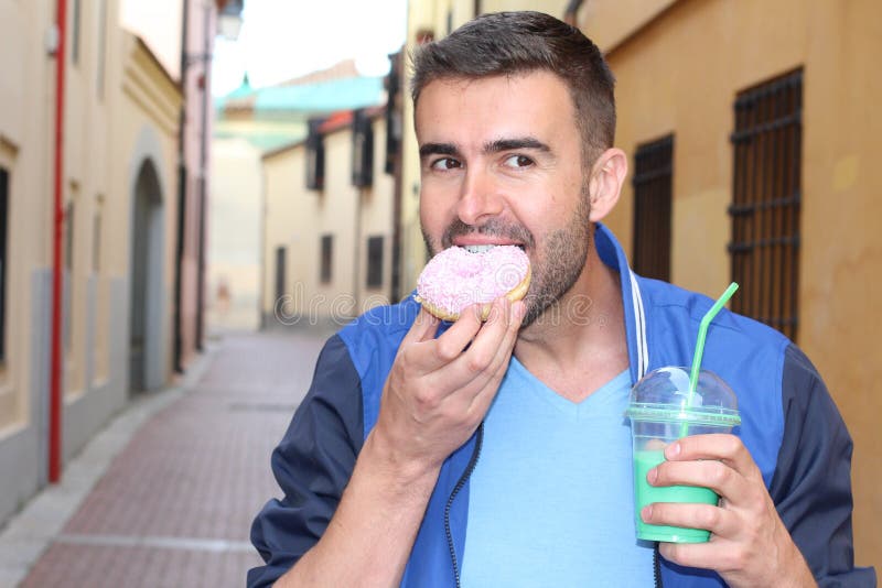 Man Eating a Donuts and Drinking a Shake Outdoors Stock Photo - Image ...