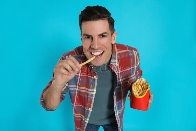 Man Eating French Fries on Light Blue Background Stock Image - Image of ...