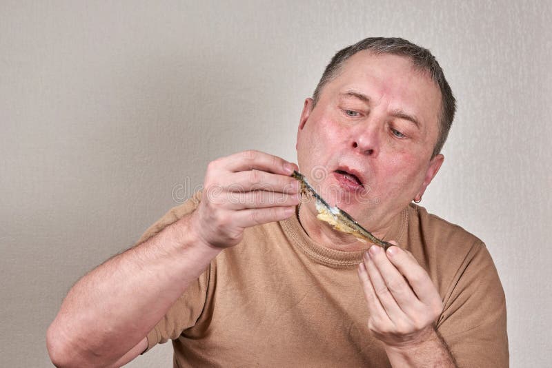 Man Eating Fried Smelt Fish Holding Fish with Hands in Front of Face ...
