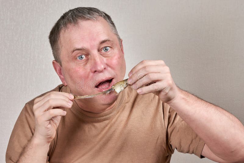 Man Eating Fried Smelt Fish Holding Fish with Hands in Front of Face ...