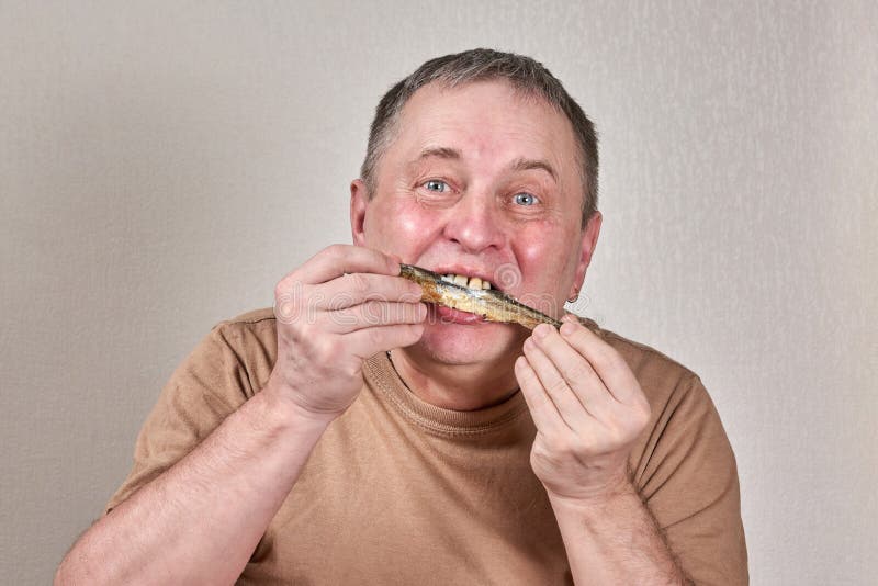 Man Eating Fried Smelt Fish Holding Fish with Hands in Front of Face ...