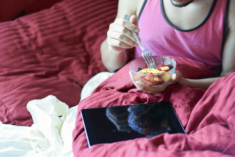 Man Eating Fruit and Using Tablet Computer Stock Photo - Image of ...
