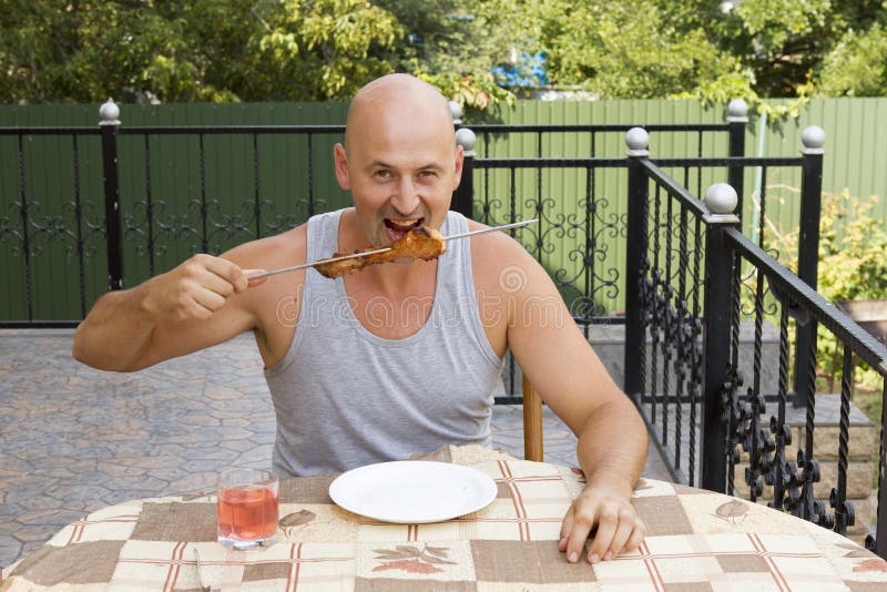A Man is Eating Meat from a Skewer Stock Image - Image of knife, male ...