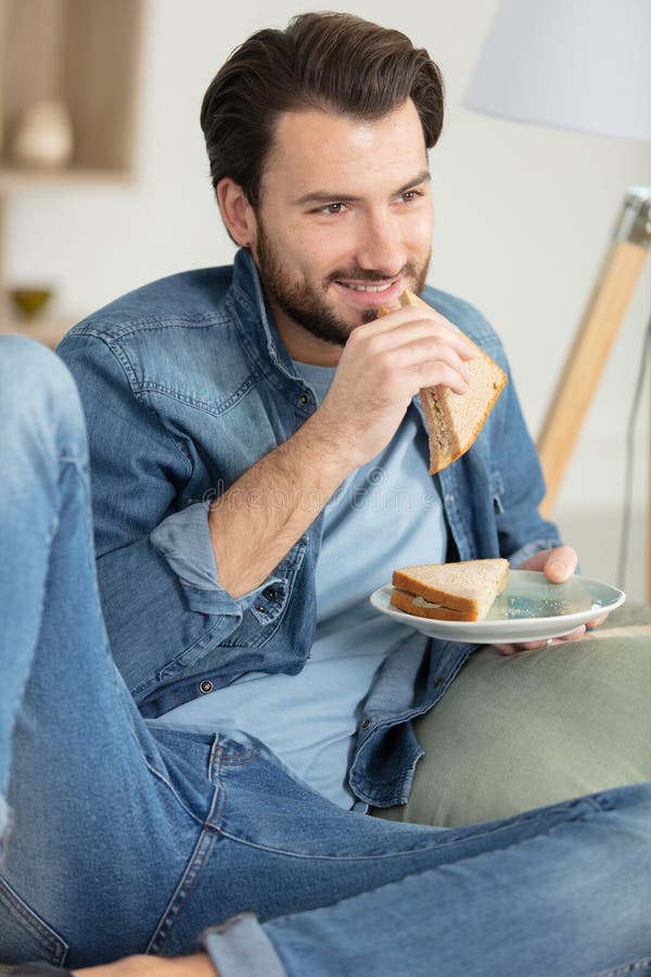 Man Eating Sandwich Sat on Sofa Stock Photo - Image of engrossed, male ...