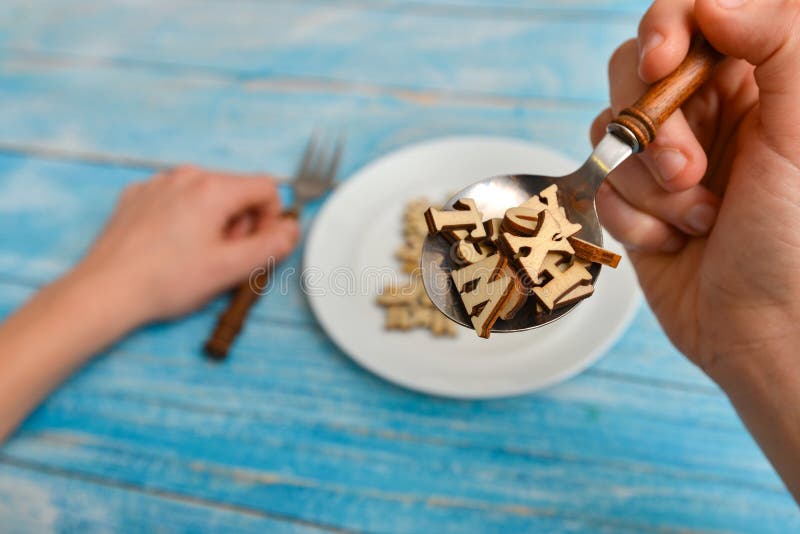 Man Eating Wooden Letters from a Spoon, on a Blue Wooden Background ...