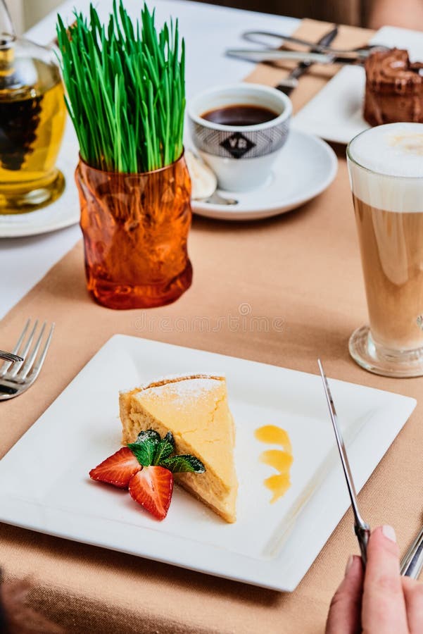 Man Eats Cheesecake with Strawberries on a White Plate on the Table in ...