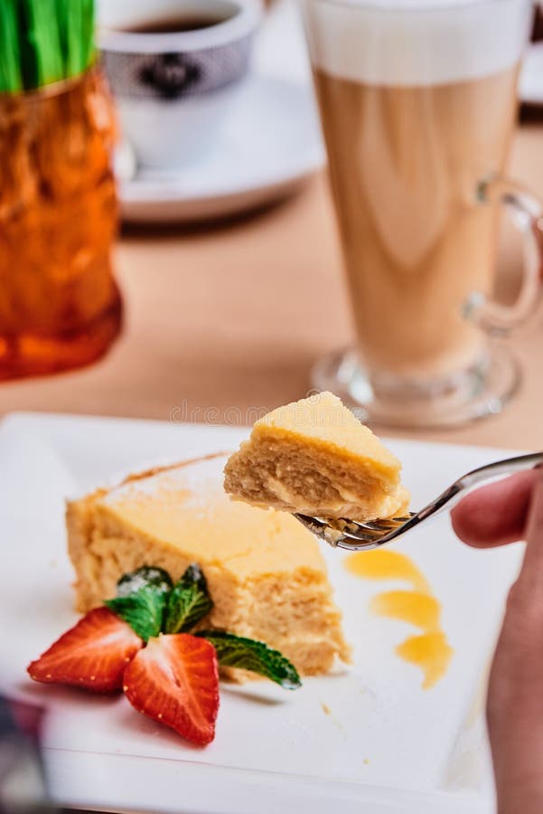 Man Eats Cheesecake with Strawberries on a White Plate on the Table in ...