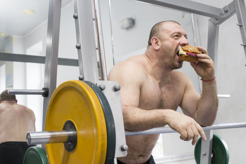 A Big Fat Hungry Man Eats a Hamburger with Meat and Cheese Stock Photo ...
