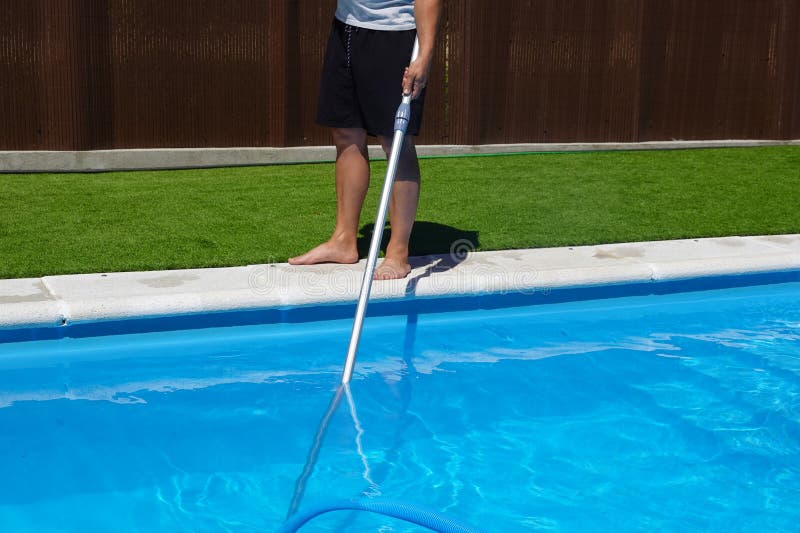 Man at the Edge of the Pool with a Pool Cleaner To Clean the Bottom of ...