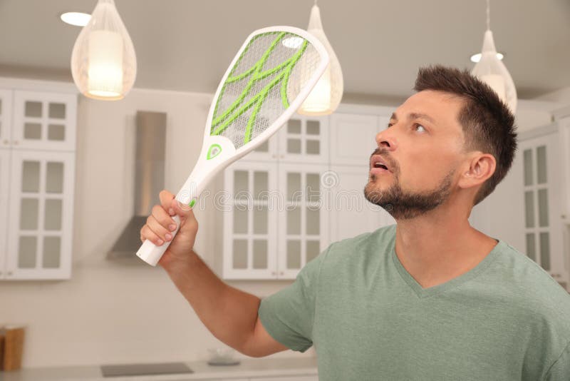 Man with Electric Fly Swatter in Kitchen. Insect Killer Stock Image ...