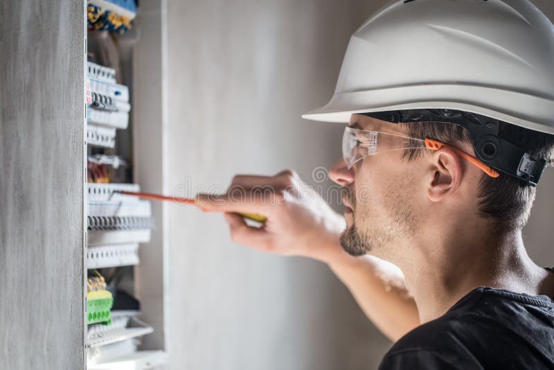 Man, an Electrical Technician Working in a Switchboard with Fuses ...