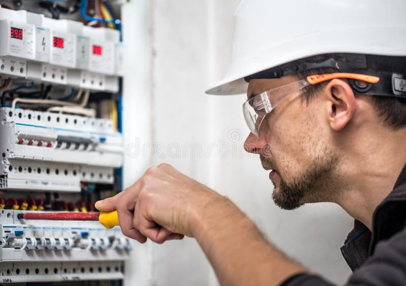Man, an Electrical Technician Working in a Switchboard with Fuses ...
