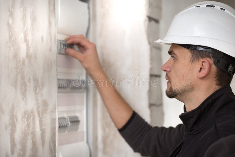 Man, an Electrical Technician Working in a Switchboard with Fuses ...