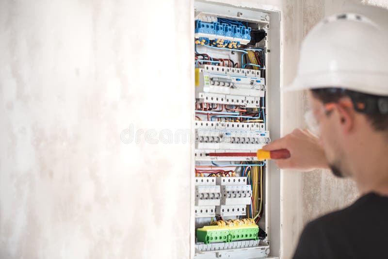 Man, an Electrical Technician Working in a Switchboard with Fuses ...