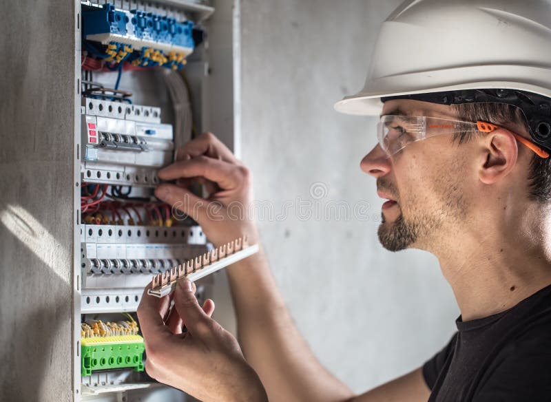 Man, an Electrical Technician Working in a Switchboard with Fuses ...