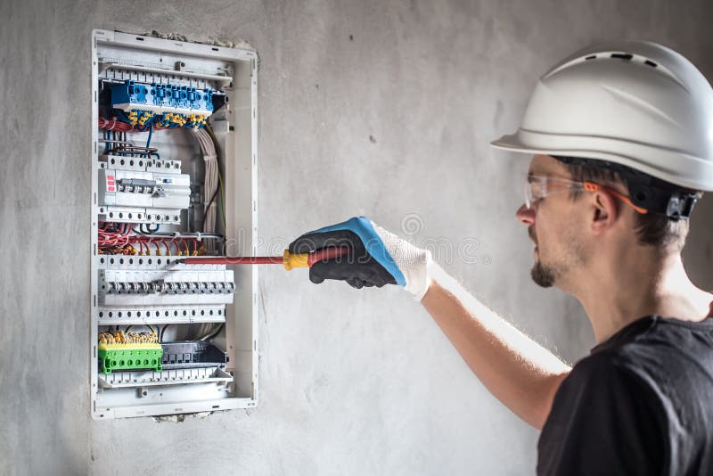 Man, an Electrical Technician Working in a Switchboard with Fuses ...