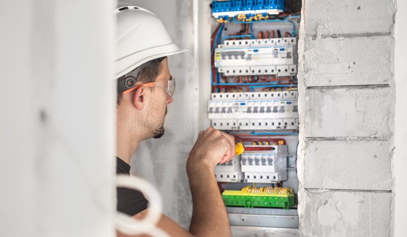 Man, an Electrical Technician Working in a Switchboard with Fuses ...