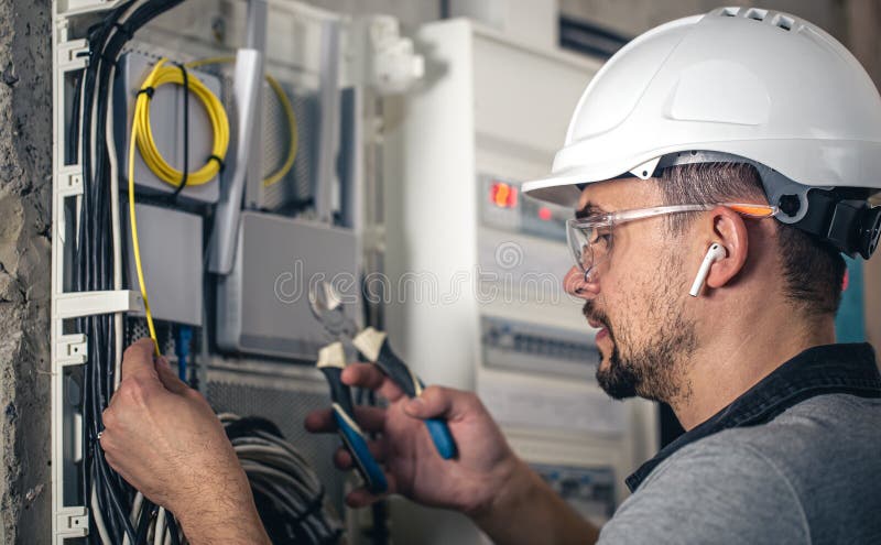Man, an Electrical Technician Working in a Switchboard with Fuses ...