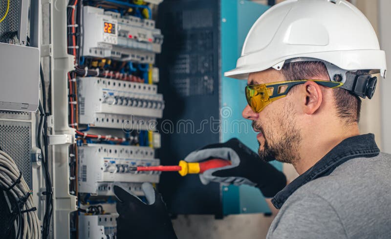 Man, an Electrical Technician Working in a Switchboard with Fuses ...