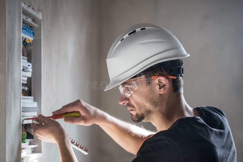 Man, an Electrical Technician Working in a Switchboard with Fuses ...