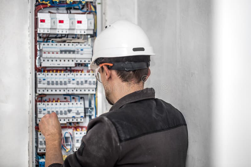 Man, an Electrical Technician Working in a Switchboard with Fuses ...