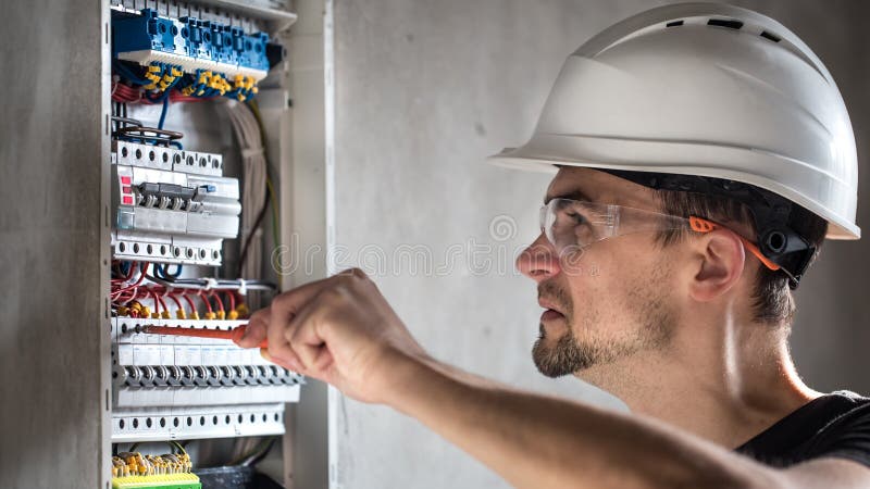 Man, an Electrical Technician Working in a Switchboard with Fuses ...