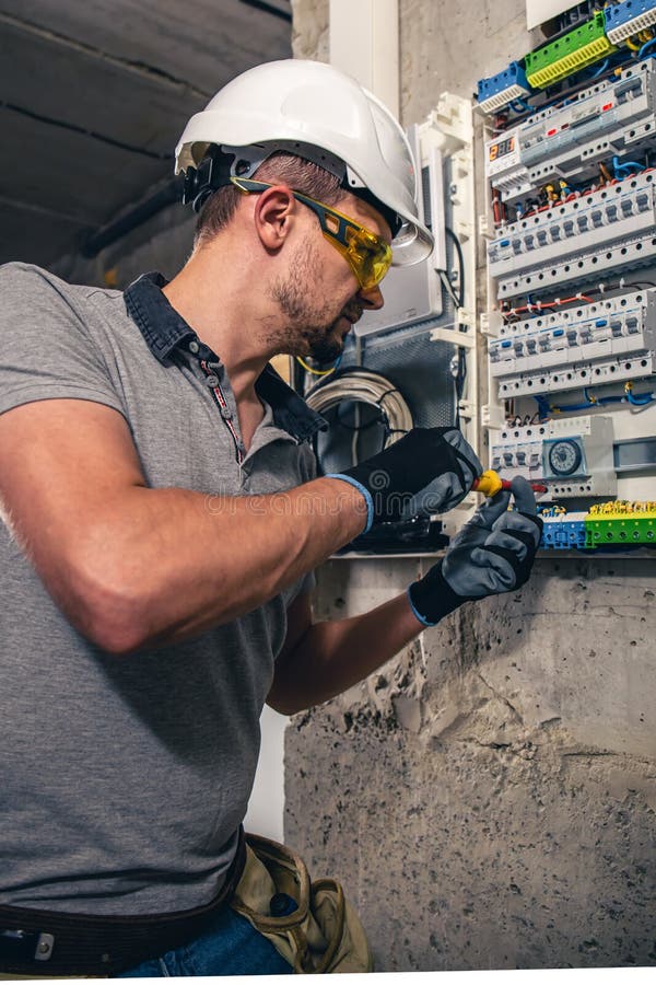 Man, an Electrical Technician Working in a Switchboard with Fuses ...