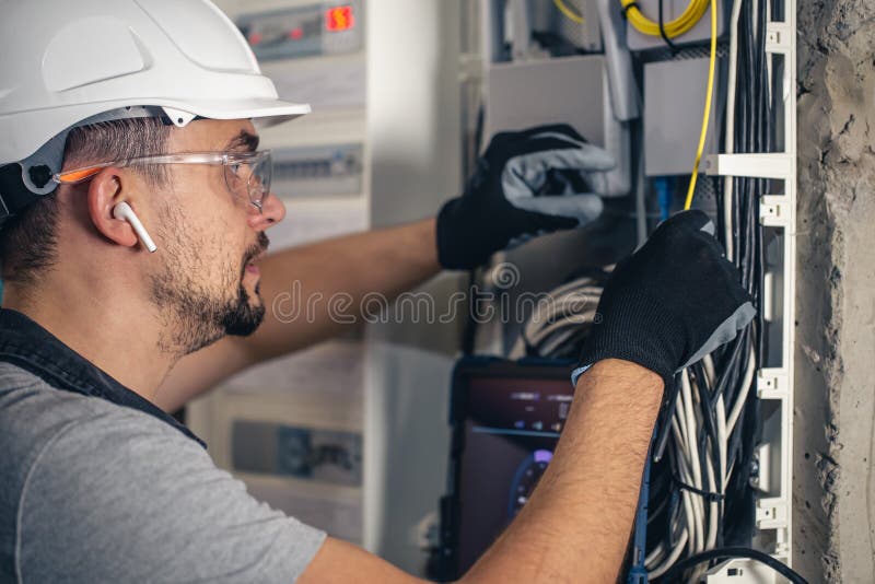 Man, an Electrical Technician Working in a Switchboard with Fuses ...