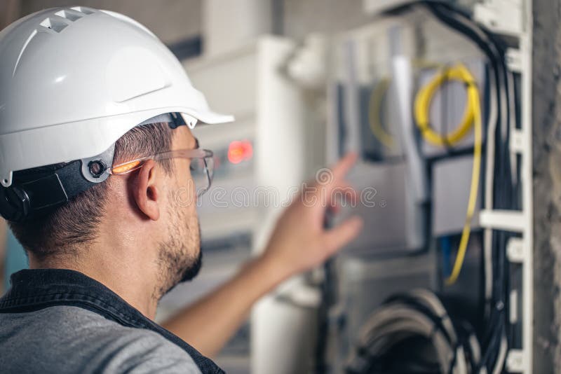 Man, an Electrical Technician Working in a Switchboard with Fuses ...