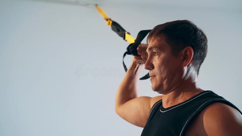 A Man Engages in the Gym Using TRX Loops. Exercise on the Muscles of ...