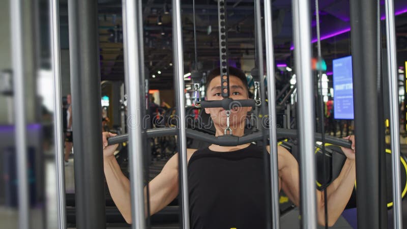 Young Asian Athlete, Determined and Focused, Engages in Weightlifting Exercises in Gym. he ...