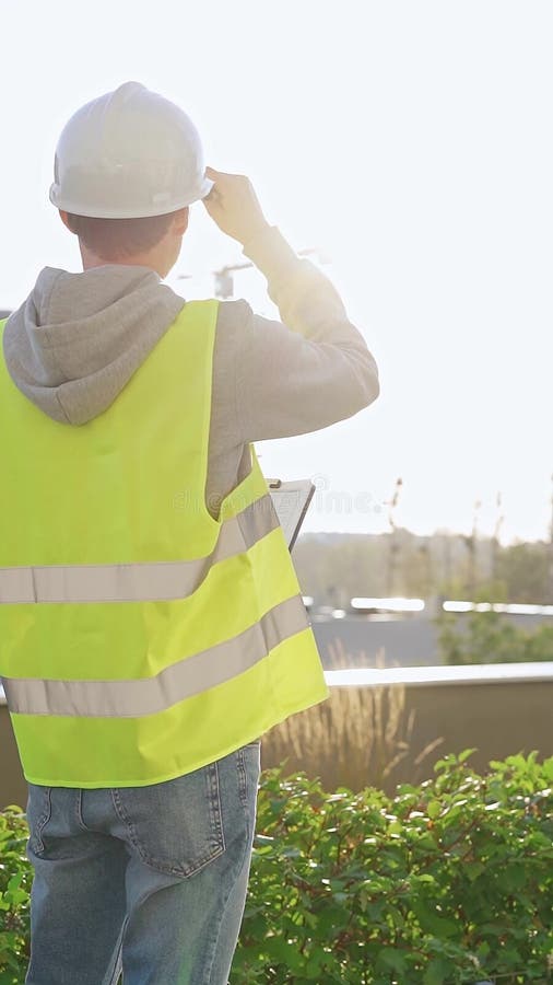 Man Engineer with White Helmet and Safety Vest is Taking Notes on a ...