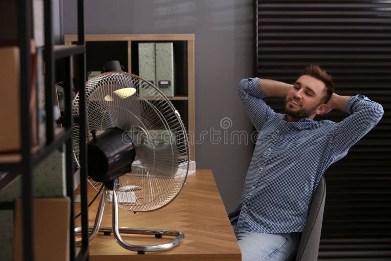 Man Enjoying Air Flow from Fan at Workplace Stock Image - Image of cool ...