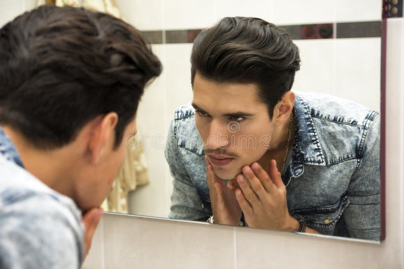 Man Examining Face in Reflection of Mirror Stock Image - Image of ...
