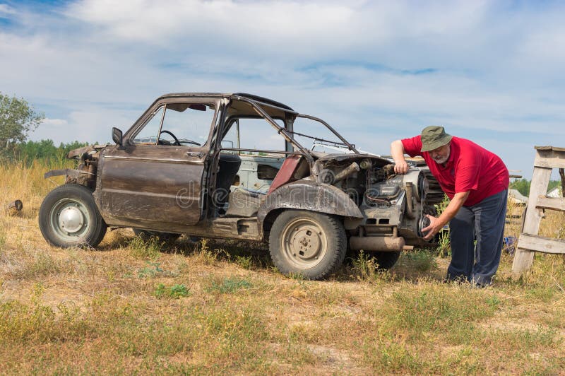 Man Examining Self-made Car Assembled from Different Ancient Vehicles ...