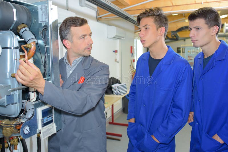 Man Explaining Workings Boiler To Two Trainees Stock Image - Image of ...