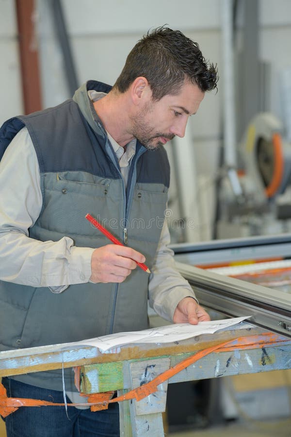 Man in Factory Stood by Window Framework Holding Plans Stock Photo ...