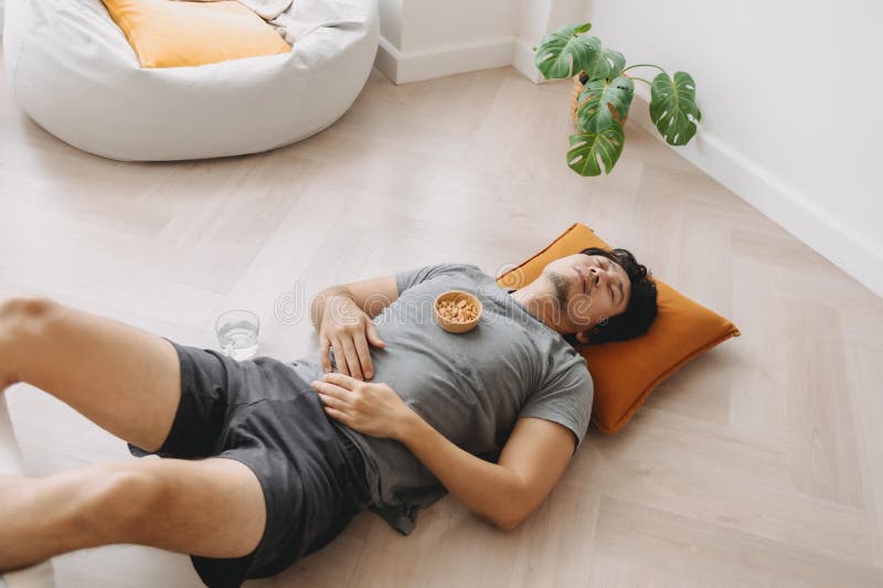 Man Falls a Sleep on the Floor while Eating Peanuts Snack in the ...