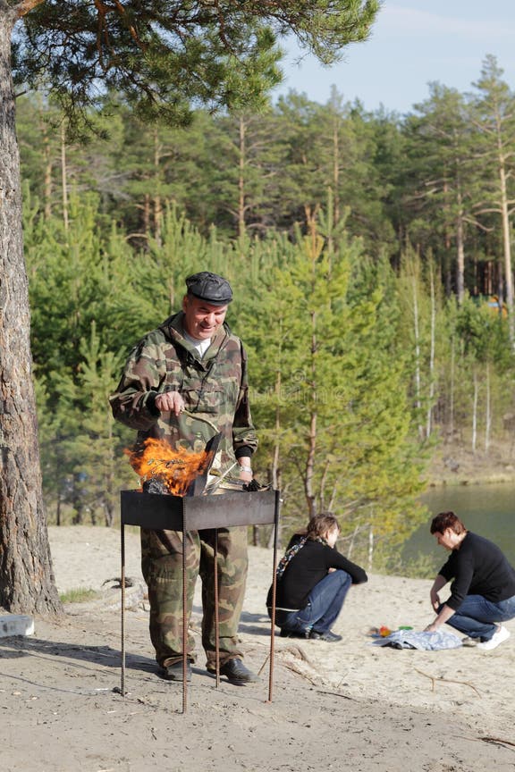 Man fanning fire in grill stock photo. Image of people - 25142742