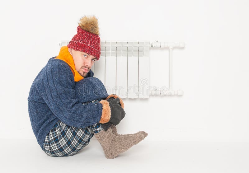 Man Feeling Cold in Hat and Pullover Sitting Close To Radiator. Gas ...